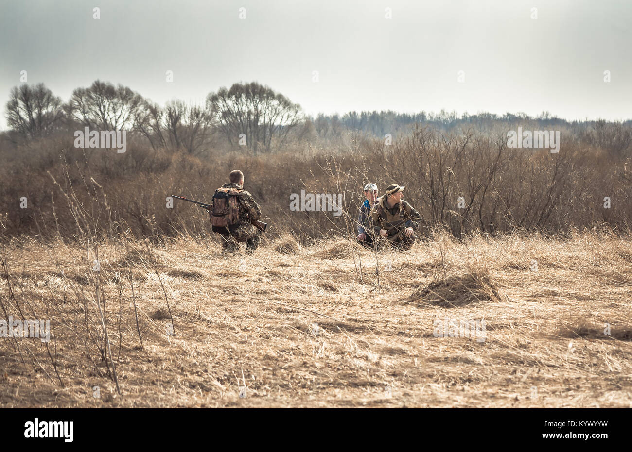 Hunting scene with hunters in rural field with dry grass during hunting ...