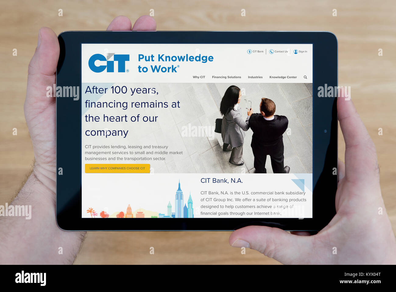 A man looks at the CIT website on his iPad tablet device, with a wooden ...