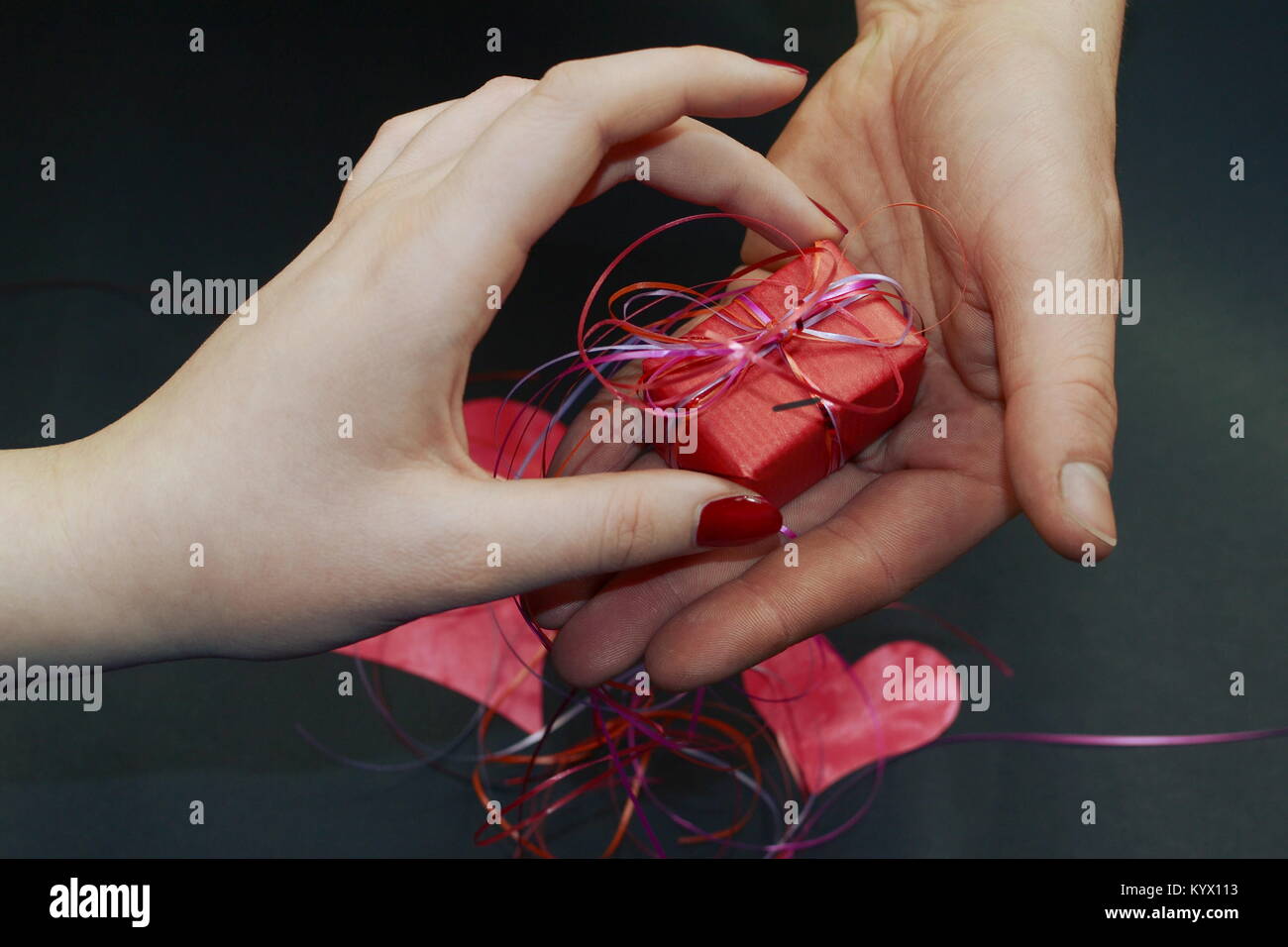 A female hand takes a red gift from male hand Stock Photo - Alamy