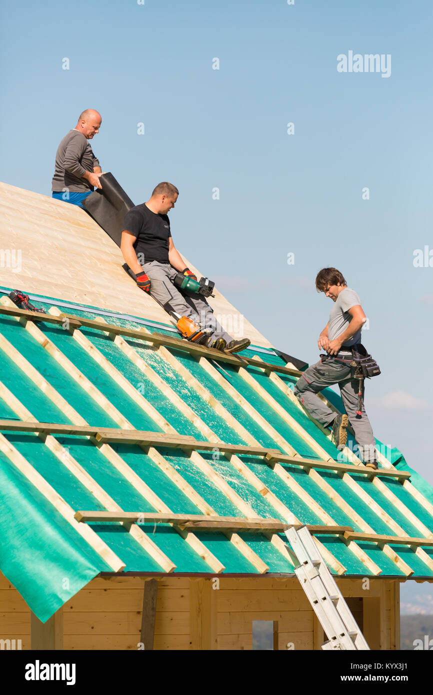 Builders at work with wooden roof construction Stock Photo - Alamy