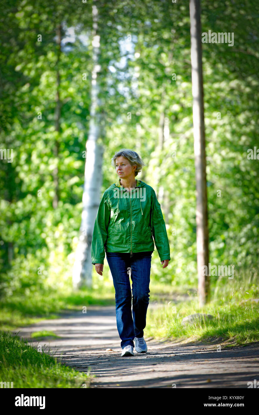 Middle aged woman taking a carefree walk in the forest Stock Photo - Alamy