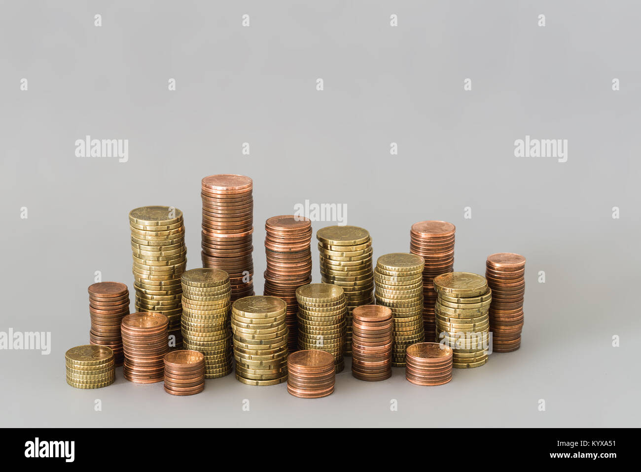 Different stacks of euro coins in front of grey background symbolizing ...