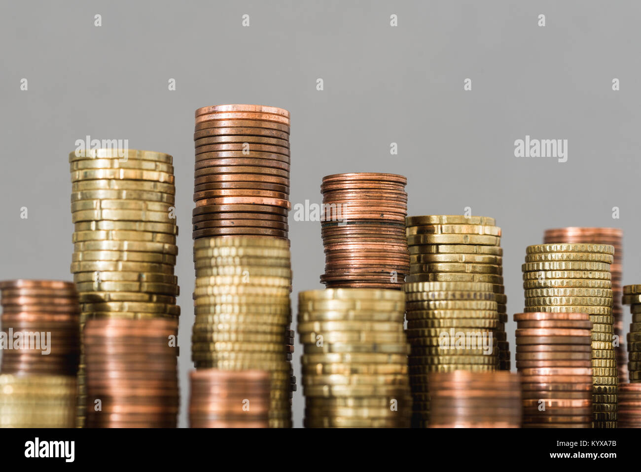 Different stacks of euro coins in front of grey background symbolizing ...