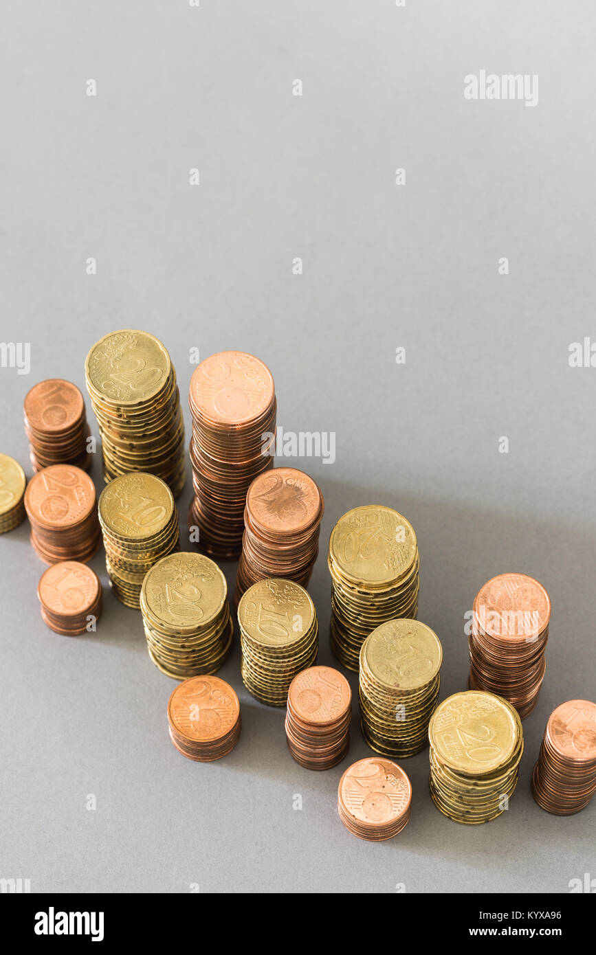 Different stacks of euro coins in front of grey background symbolizing ...