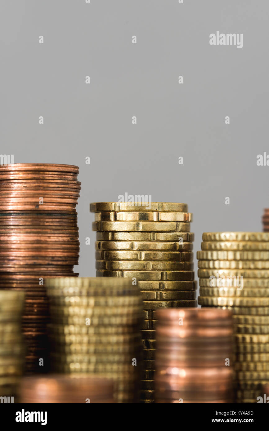 Closeup of different stacks of euro coins in front of grey background ...