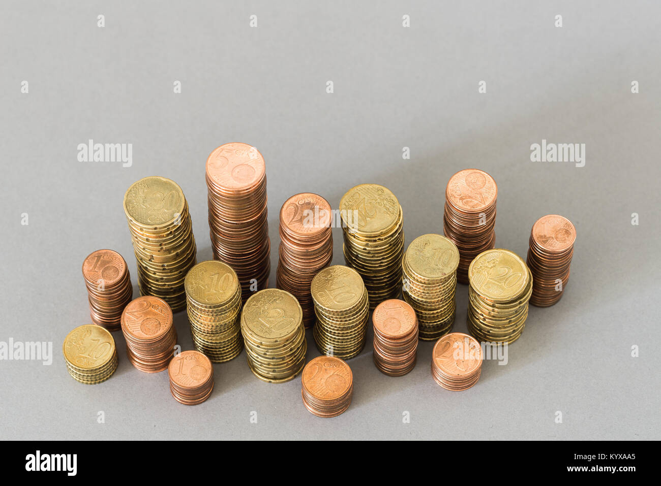 Different stacks of euro coins in front of grey background symbolizing ...