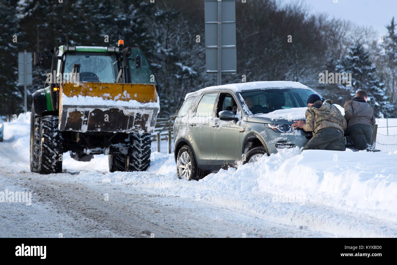 Drivers help to push a vehicle back on the road after heavy snow made ...