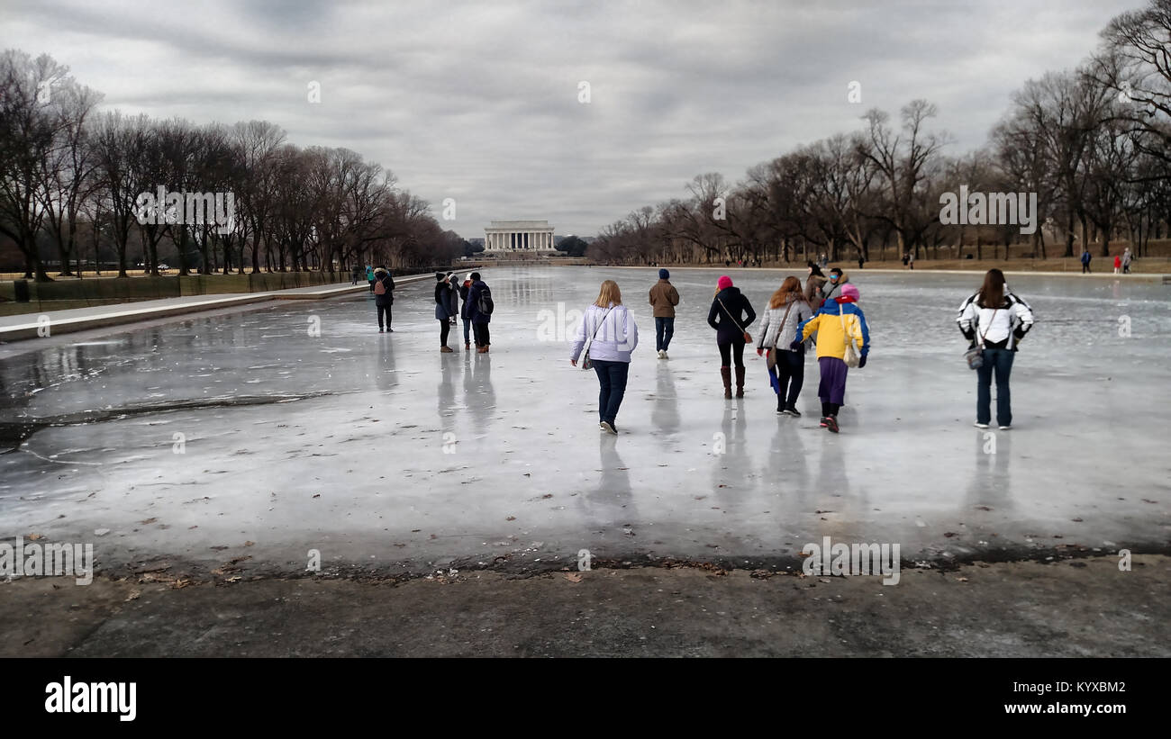 People walk on the ice of the frozen reflecting pool of Lincoln ...