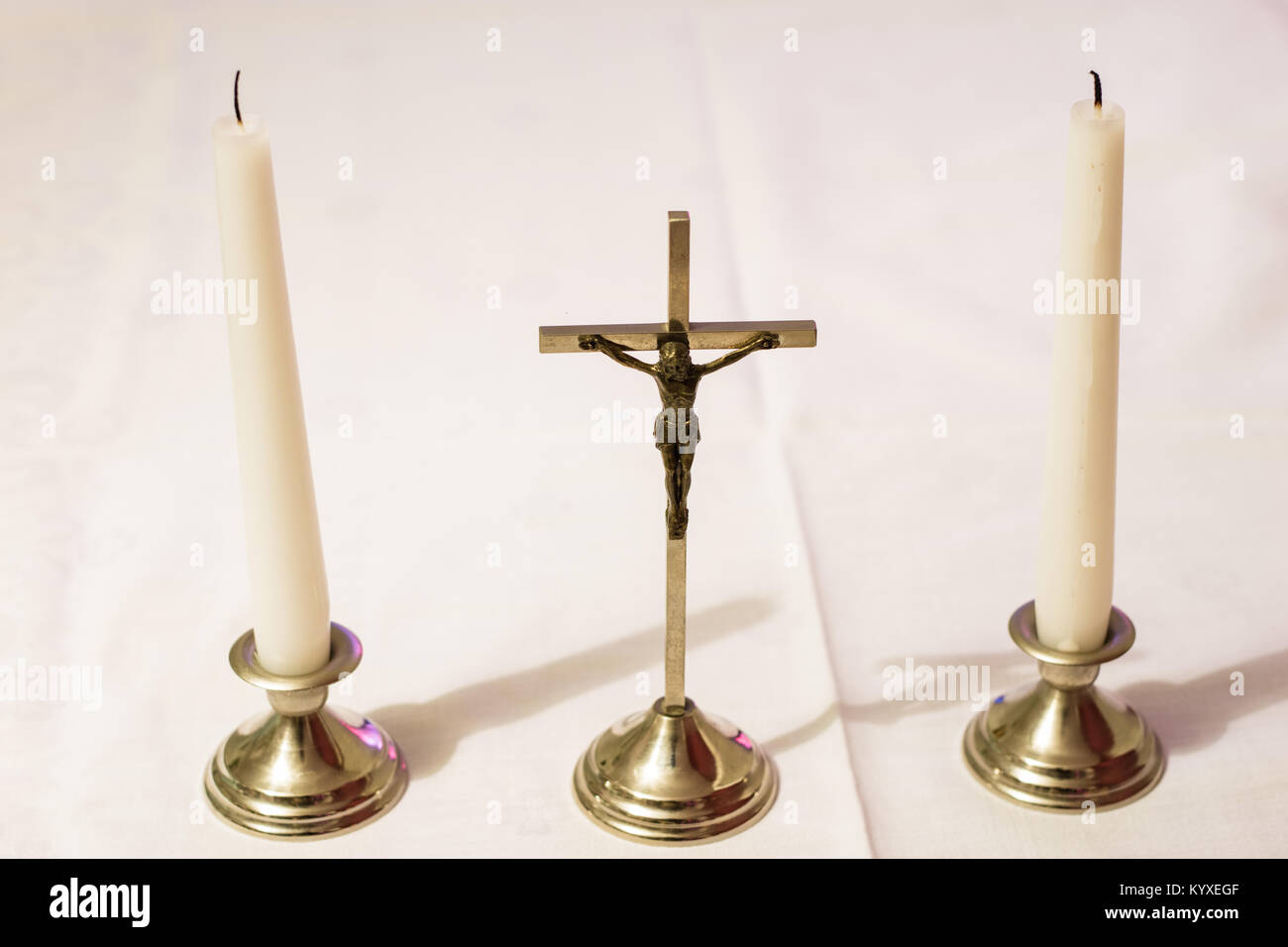 Cross and candles on a white tablecloth. Carol singing, cross and ...