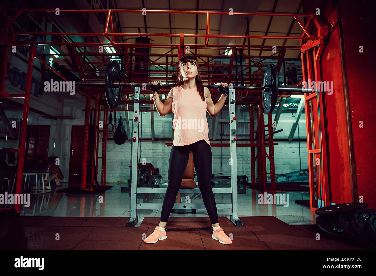 Gorgeous young fitness woman crouch and doing squad exercise with a bar ...