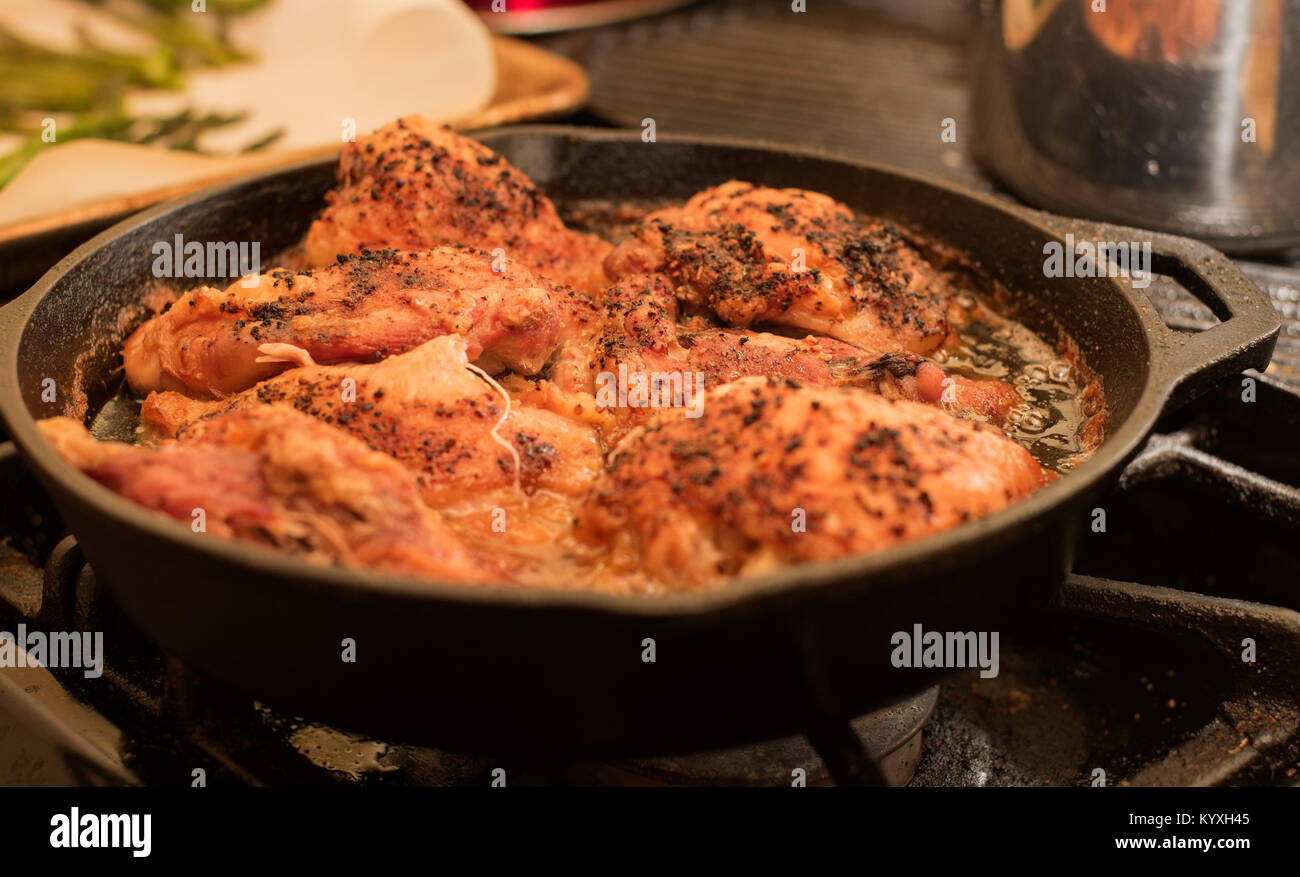 Roasted and seasoned chicken sitting in a cast iron pan on a gas stove ...