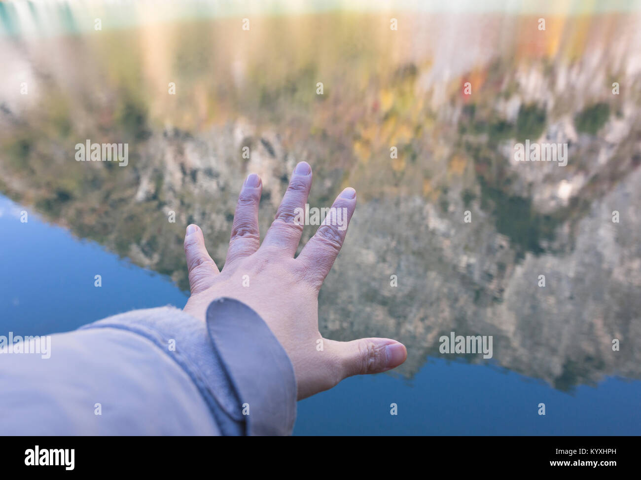 A hand stretched out into the lake, and the water reflected the colored ...