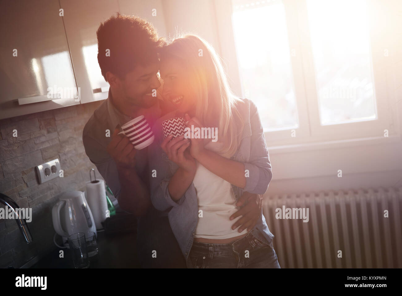 Beautiful young couple hugging and drinking coffee in kitchen Stock ...