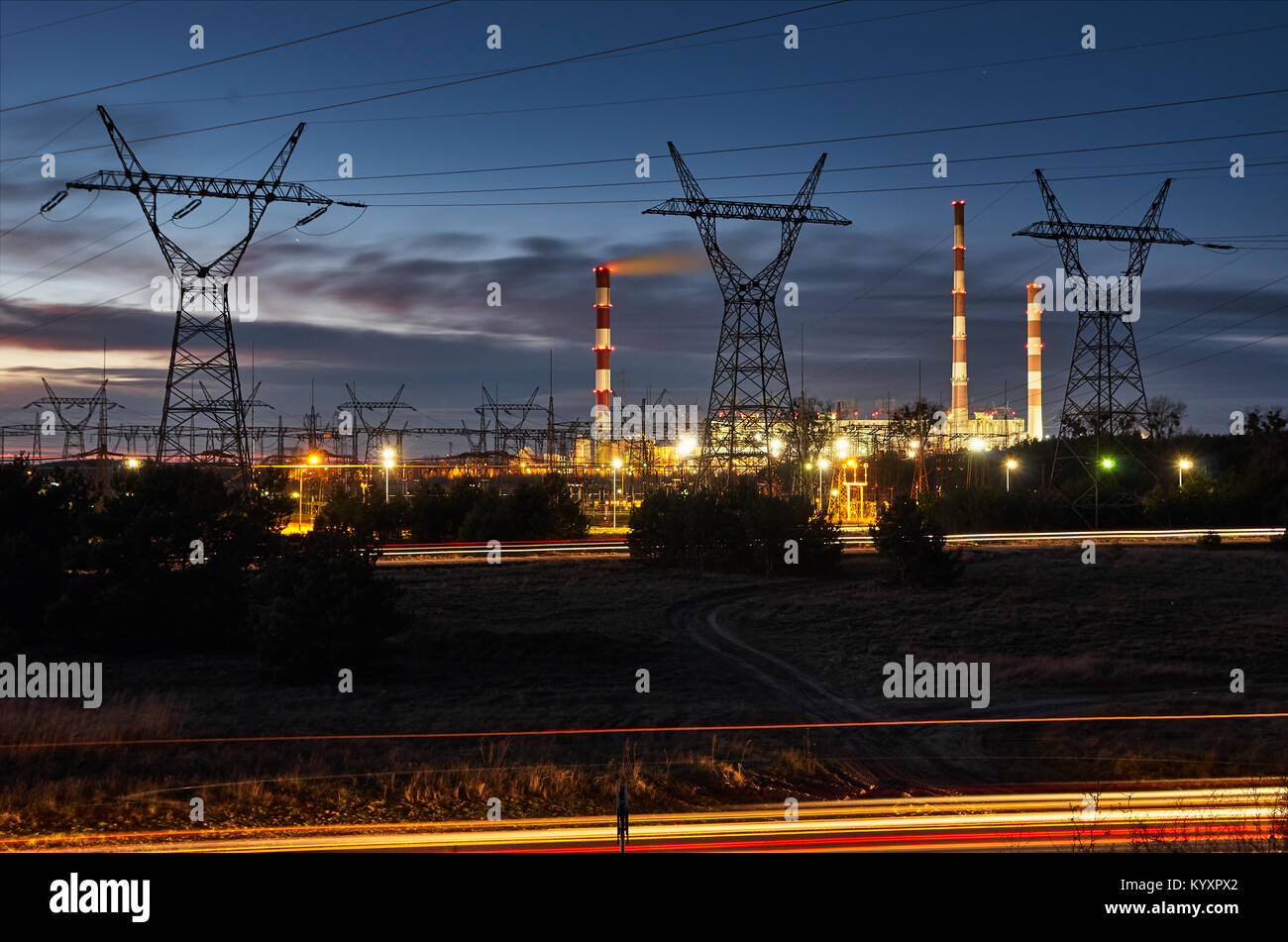 Illuminated power plant with chimneys and poles at night Stock Photo ...