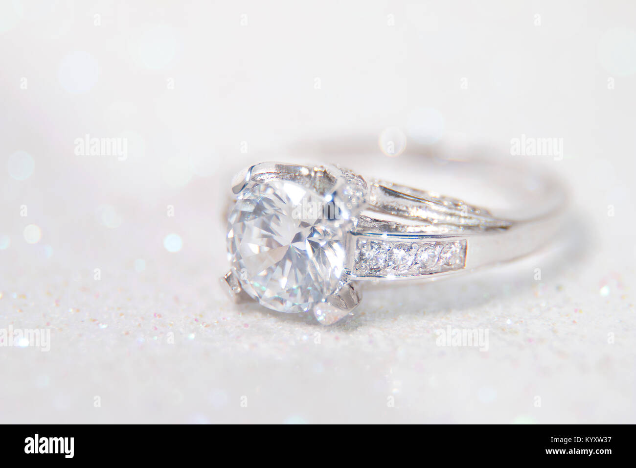 Closeup of a sparkly engagement ring lying on a sparkling background ...