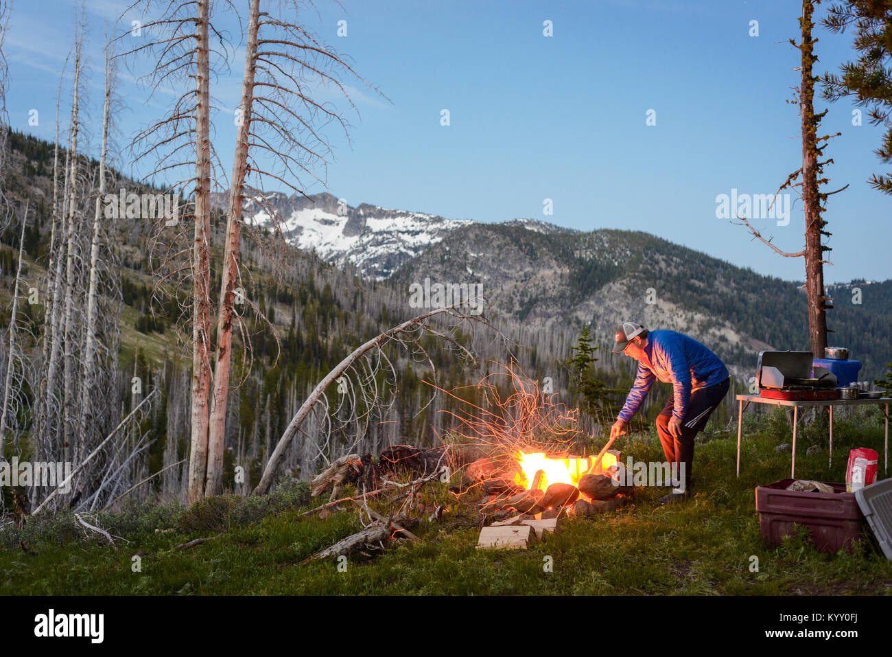 Side view of hiker burning wood in campfire at campsite against ...