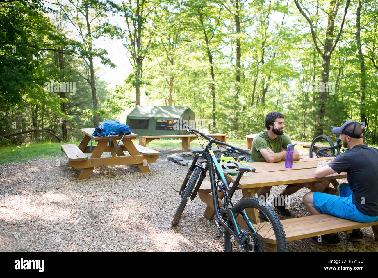 Male hikers sitting on picnic table at campsite Stock Photo - Alamy