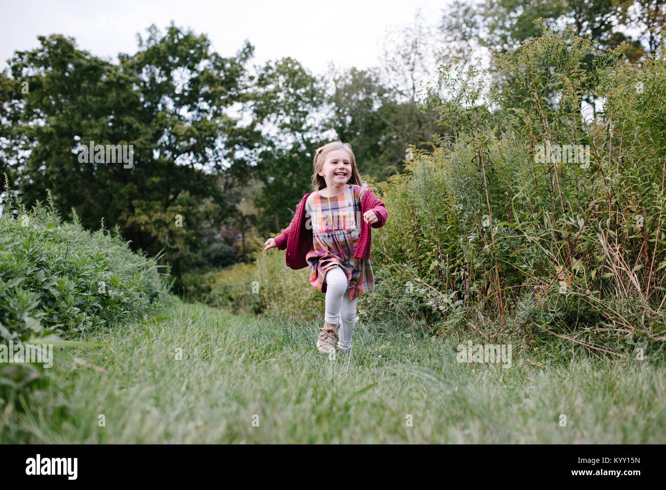Full length of cheerful girl running on field at park Stock Photo - Alamy