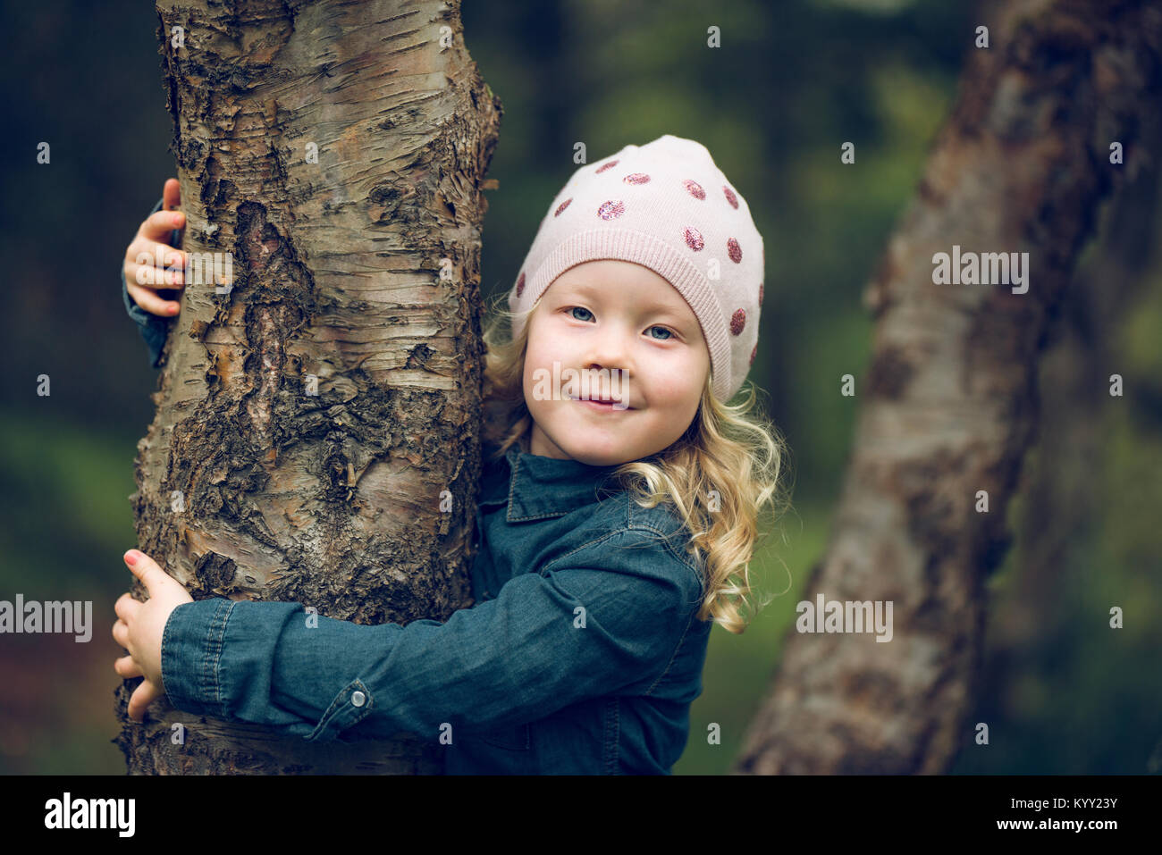 Portrait of cute girl embracing tree trunk at park Stock Photo - Alamy