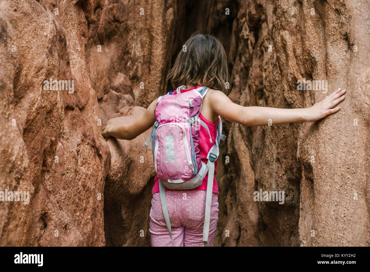 Rear view of girl with backpack exploring amidst rock formations Stock ...