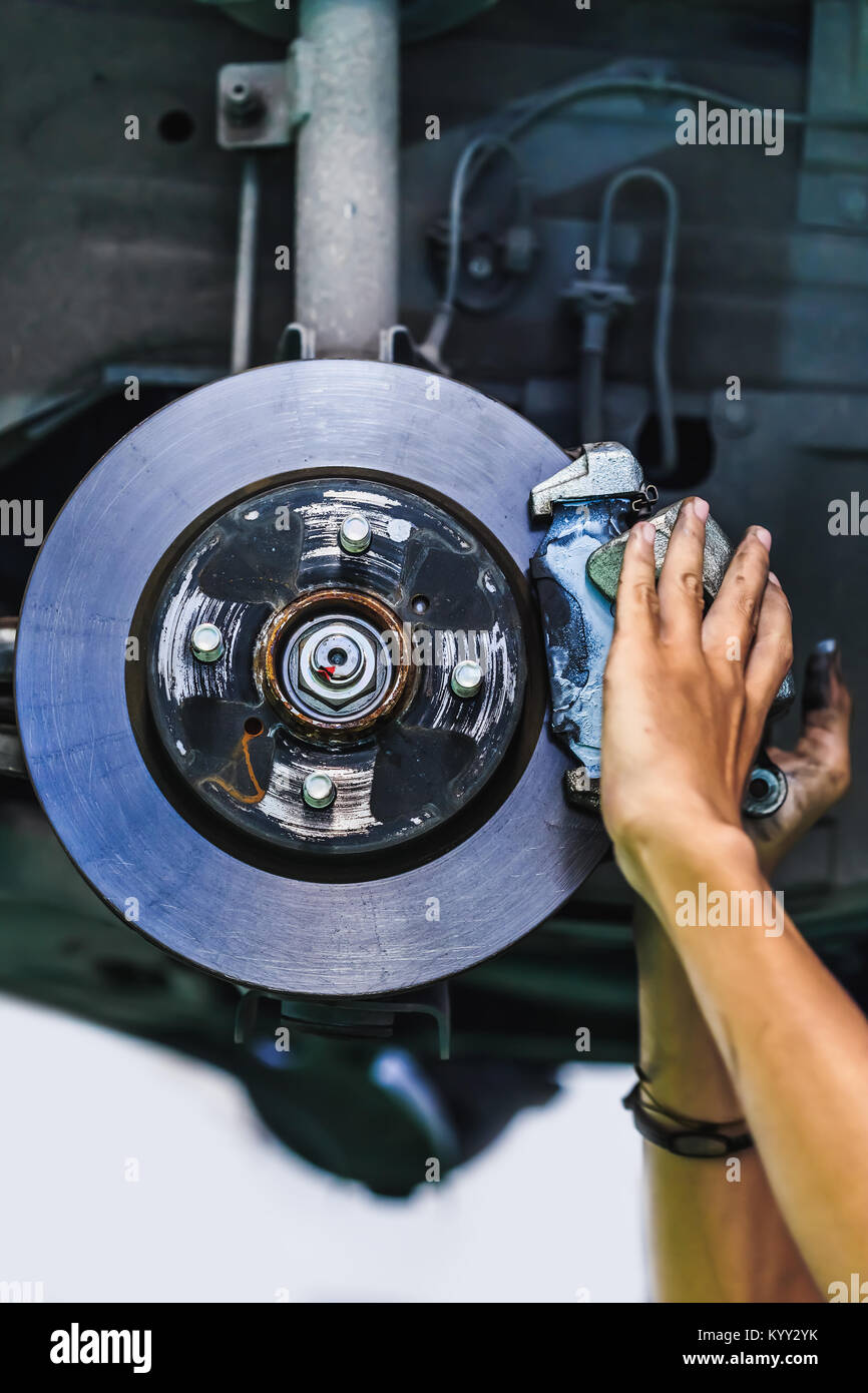 Hands of a mechanic install brake lining onto a car disc brake Stock ...