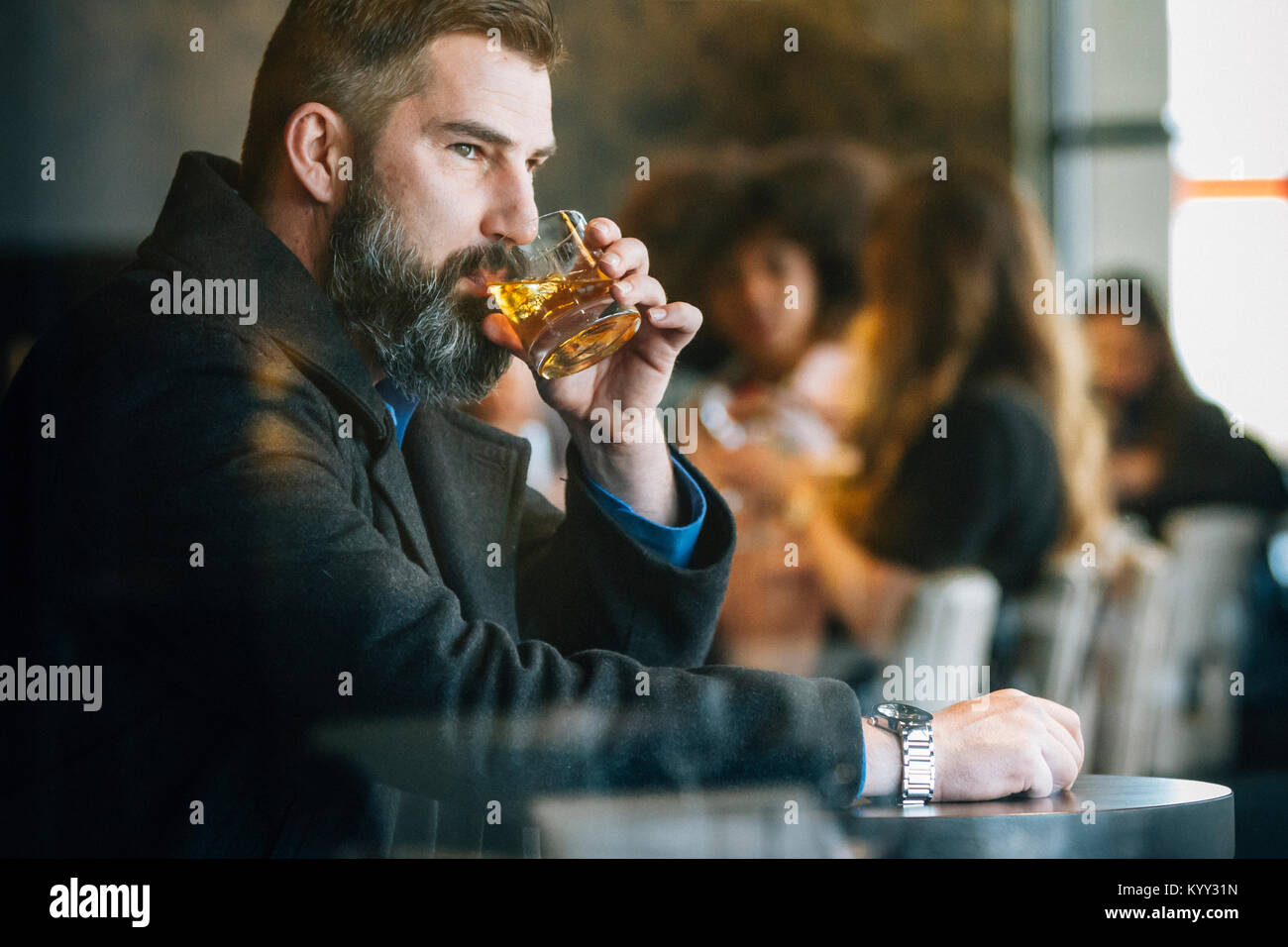 Thoughtful businessman drinking alcohol in hotel seen though window ...