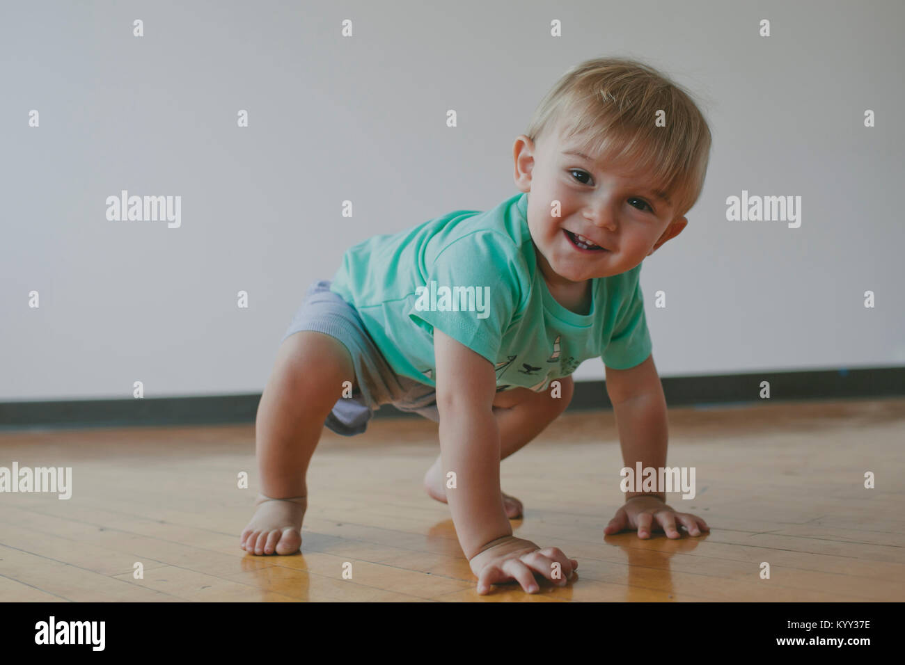 Portrait of cute baby boy crouching against wall at home Stock Photo ...