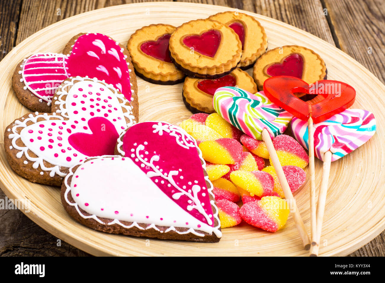 Set of sweets in the shape of heart on plate on wooden background ...