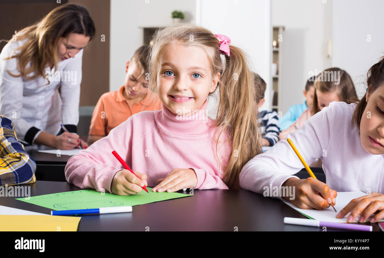 admiring little children with teacher drawing in classroom on the ...