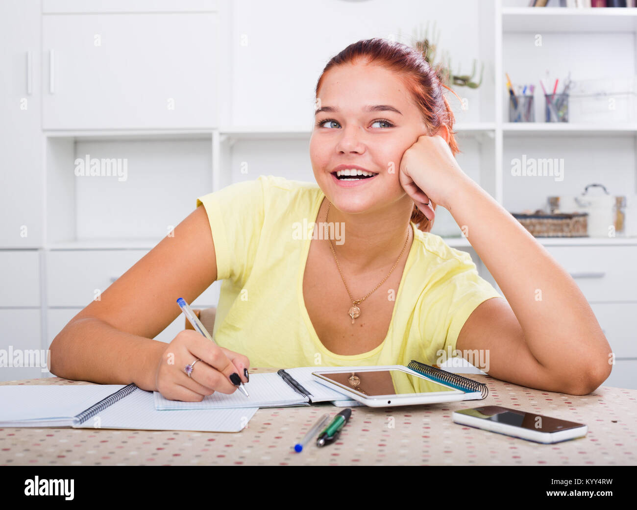 positive teenager girl taking notes while studying at home Stock Photo ...