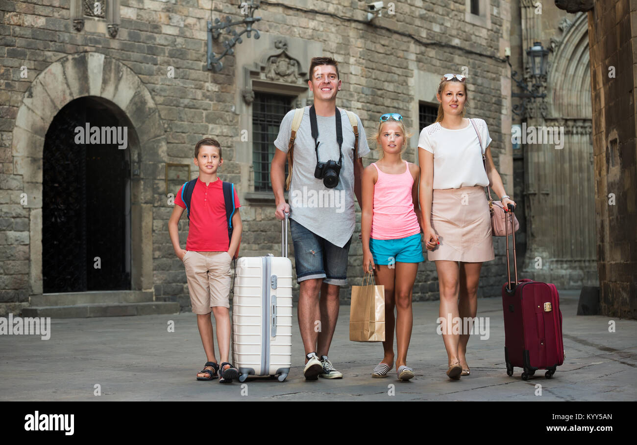Young smiling family of tourists with two kids walking around city with ...