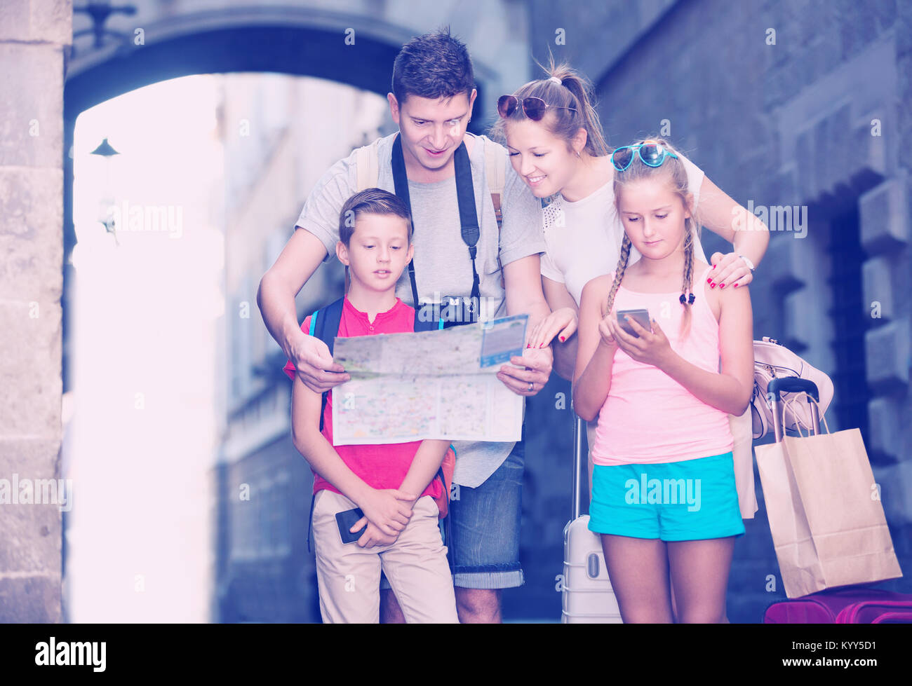 Young family of tourists looking for destination using city map and ...