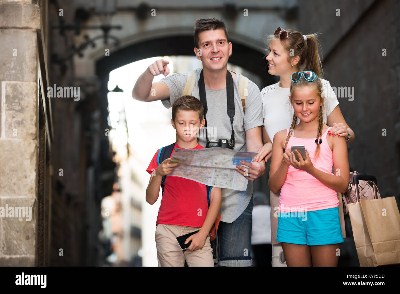 Glad family of tourists looking for destination using city map and ...