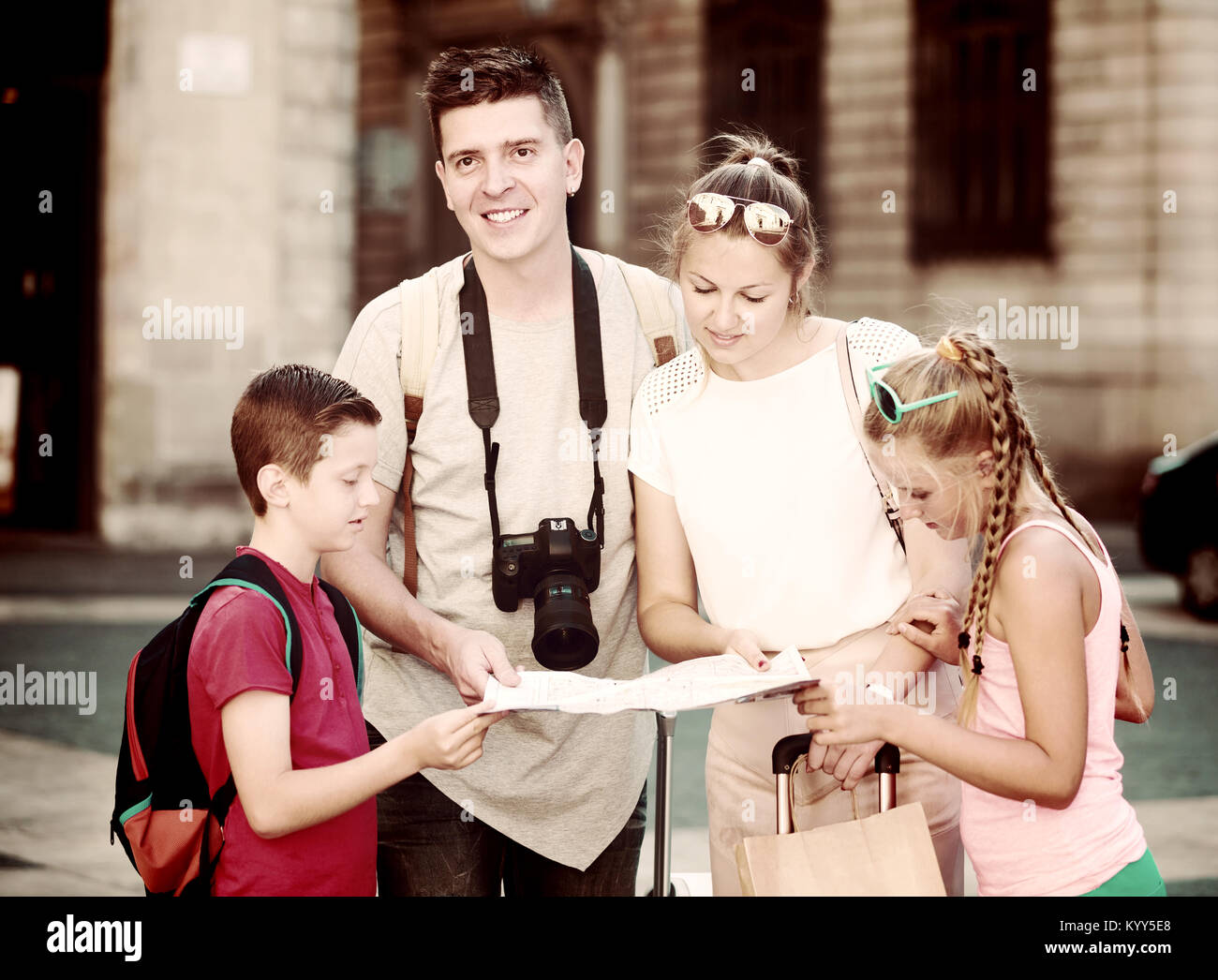 Young smiling family of tourists with two kids looking for destination ...