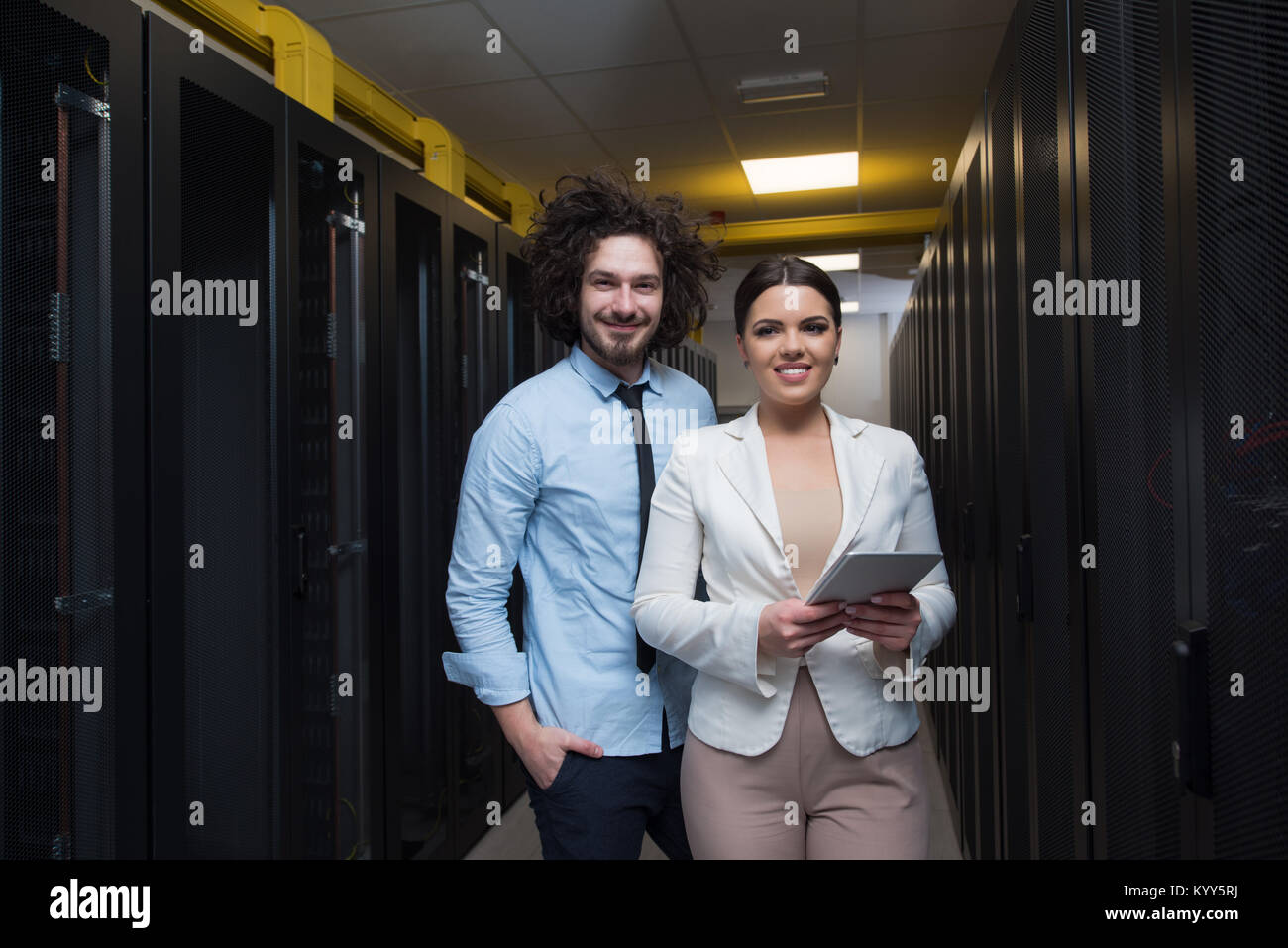 Young IT engineer showing working data center server room to female ...
