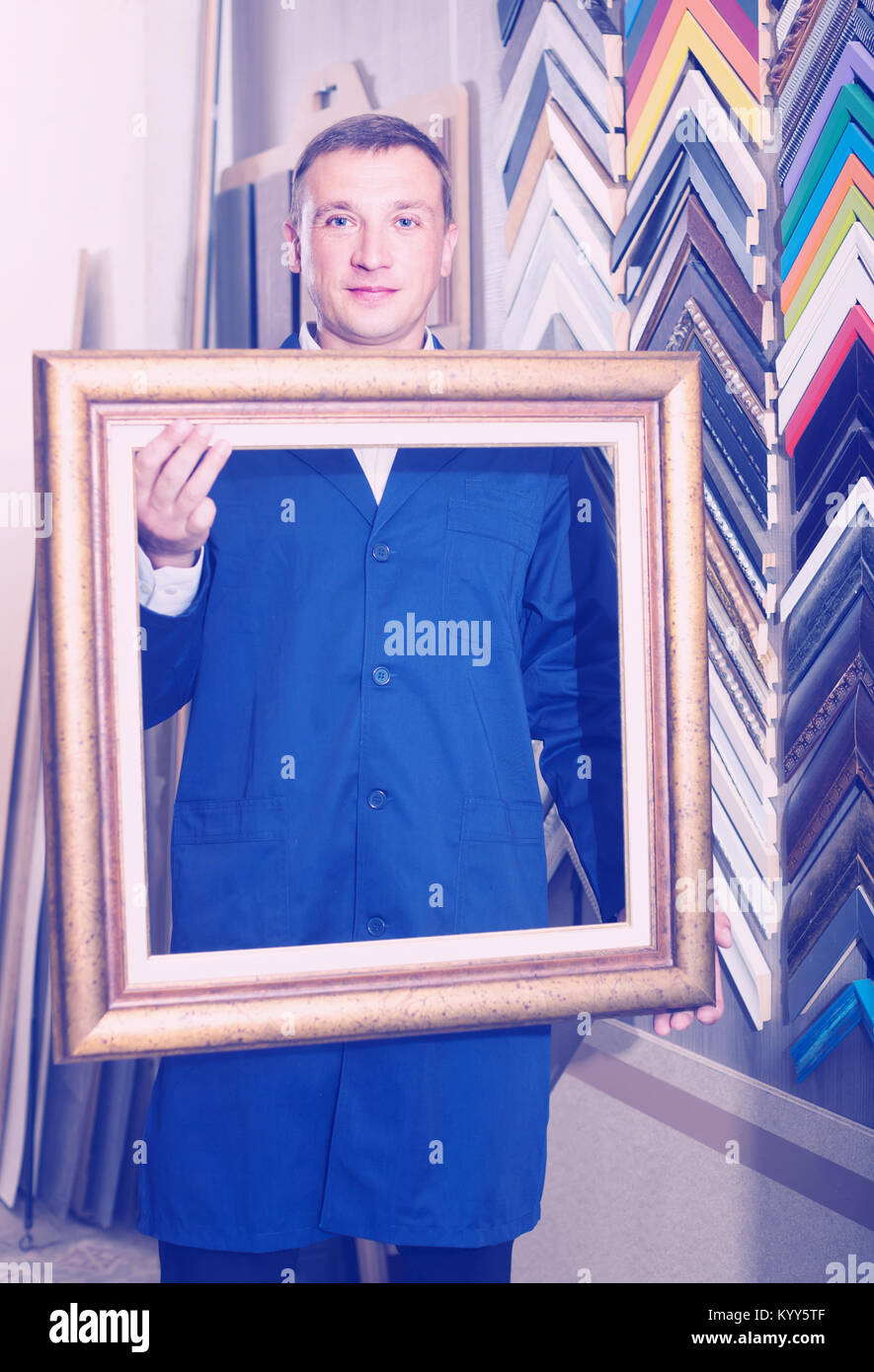 portrait of smiling spanish man seller working with picture frames in ...