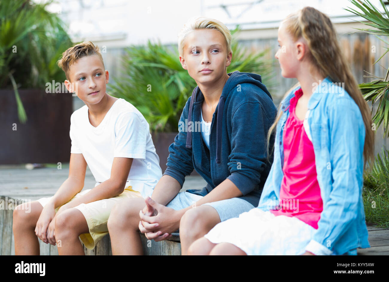 Group of positive children relaxing and chatting in town square garden ...