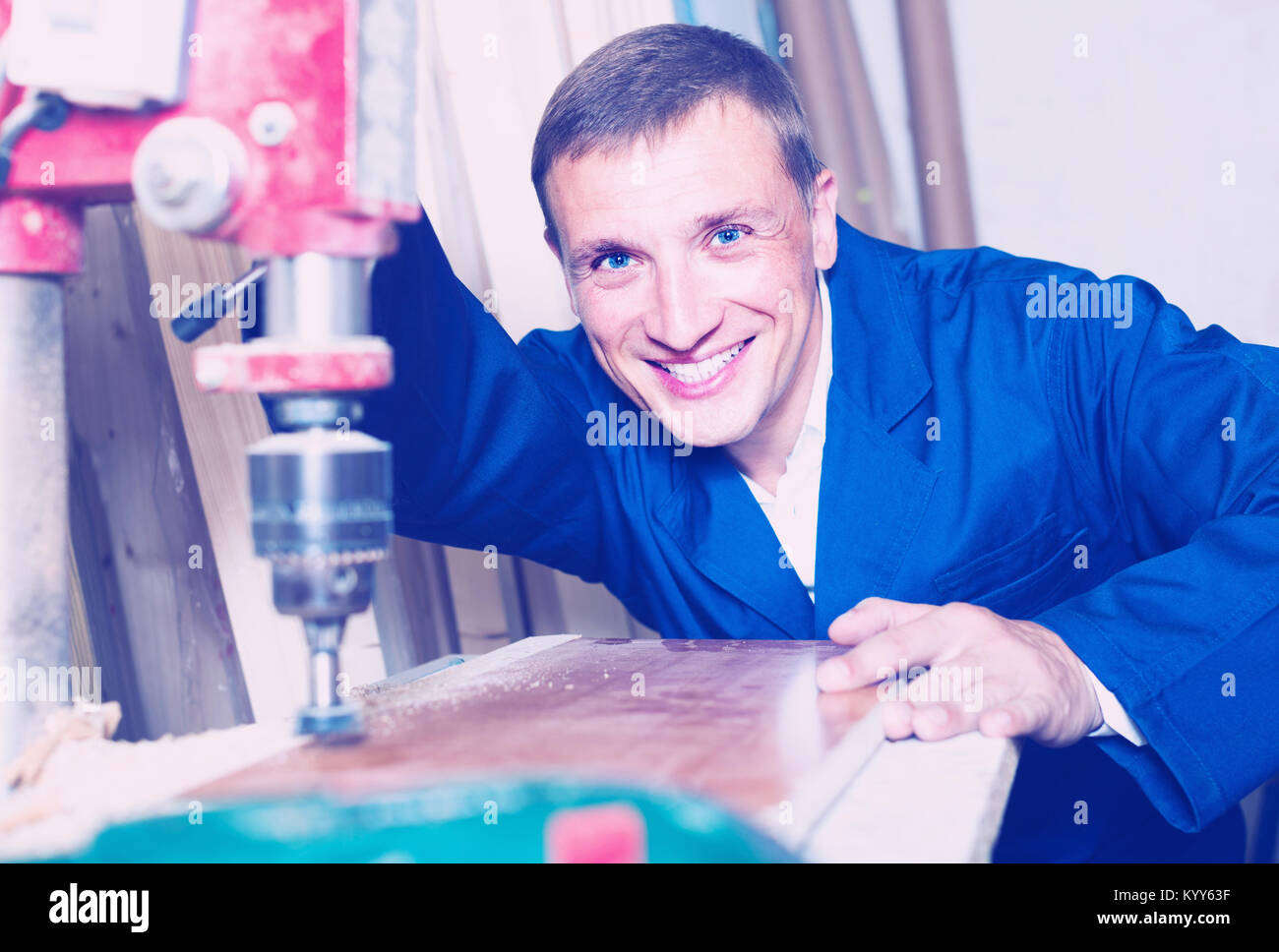 Cheerful workman 40s drilling planks using electrical screwdriver in ...