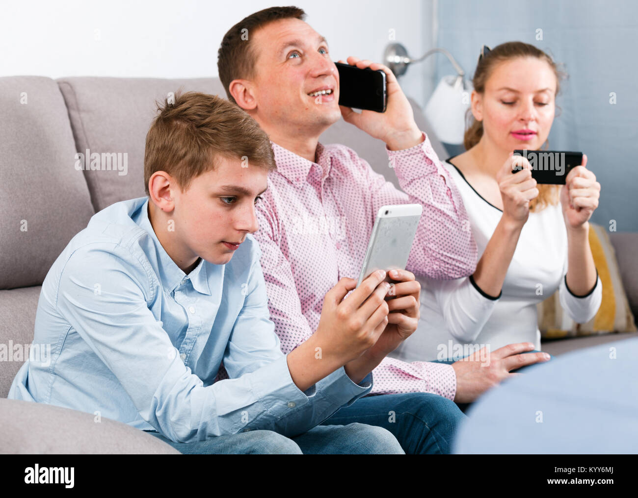 Family members spending time playing with smartphones at home Stock ...