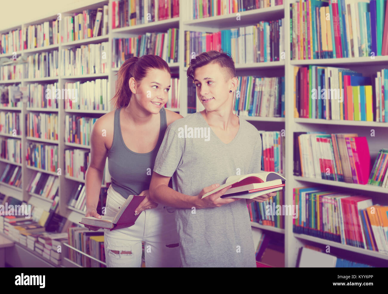 portrait of smiling european teenage boy and girl customers looking at ...