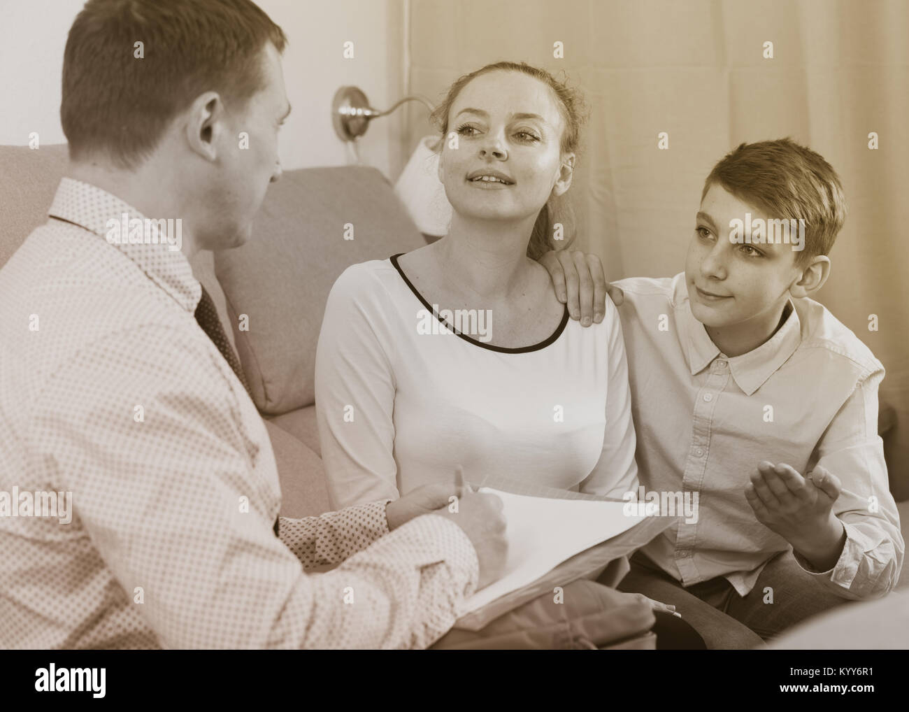 Smiling middle-aged mother and son signing agreement papers at home ...