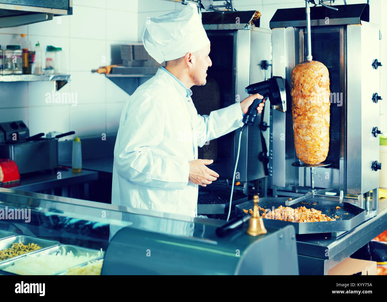 happy european mature man chef wearing uniform cutting meat for kebab ...