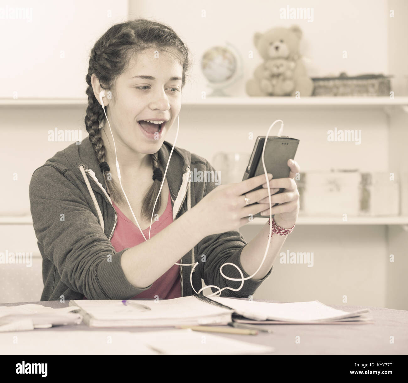 Smiling girl texting with her phone and listening to music at home ...
