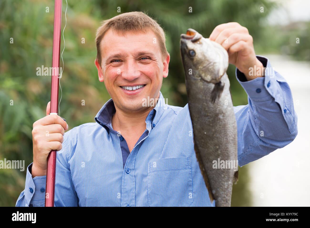 Positive fisherman holding catch freshwater fish in hands Stock Photo ...