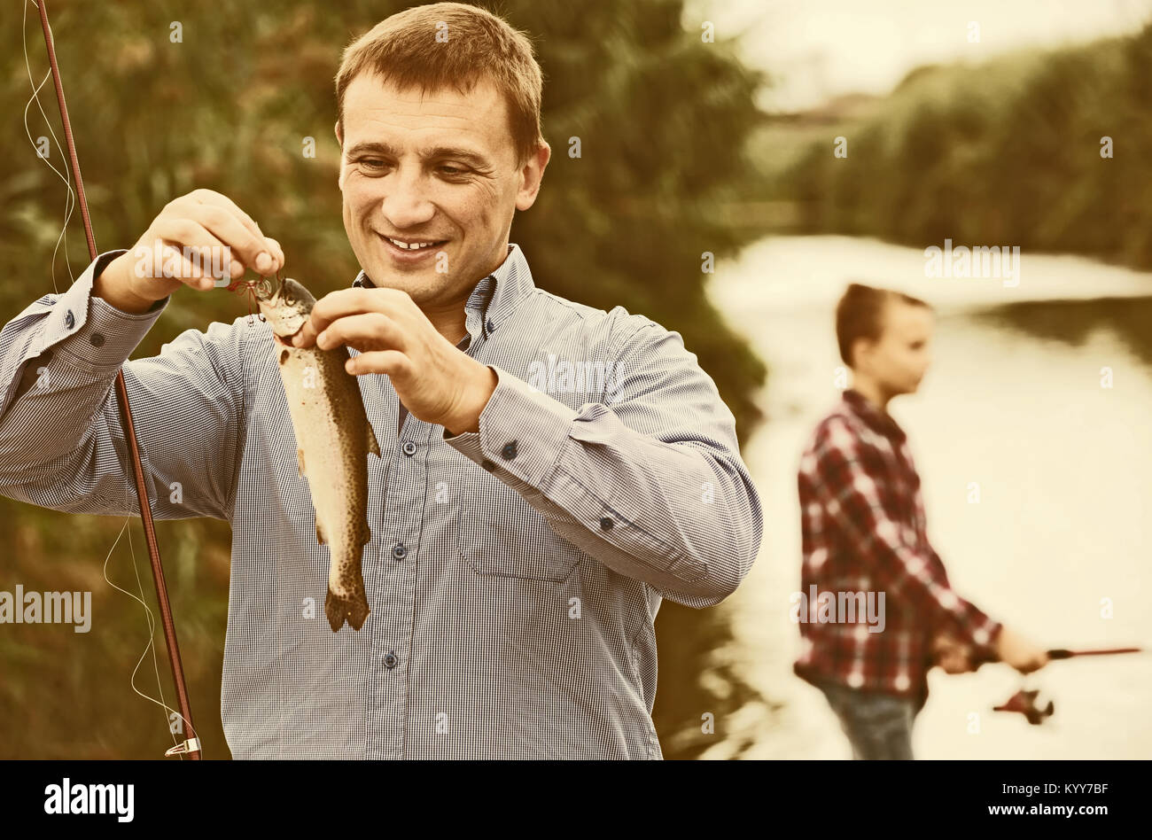 Glad man holding catch fish on hook in hands outdoors Stock Photo - Alamy