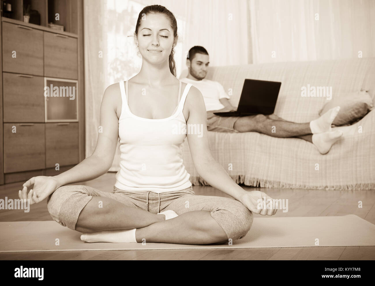 Relaxed girl in yoga position and lazy guy on sofa at home Stock Photo ...