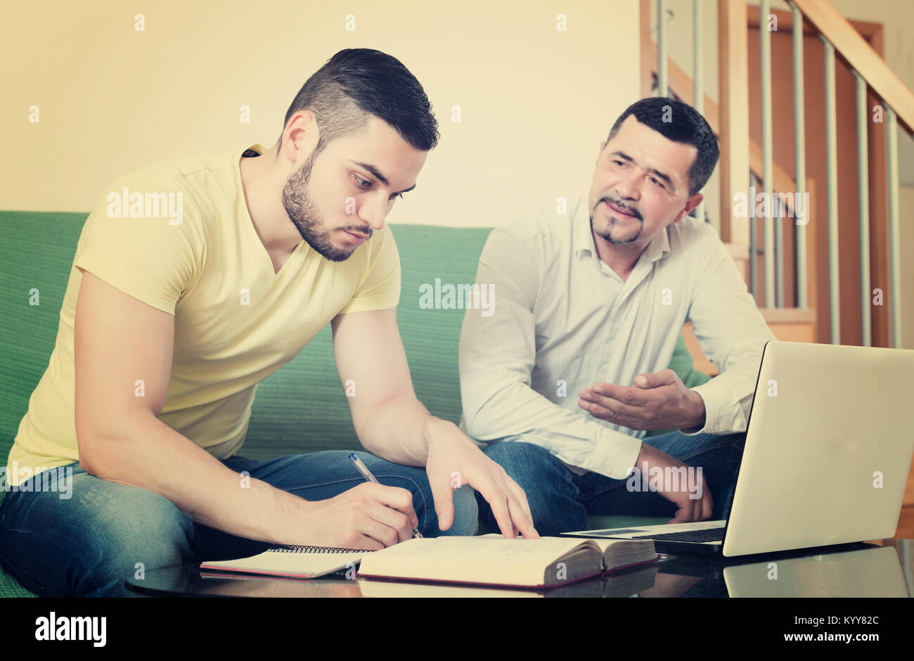 Mature professor giving private lesson to serious young student at home ...
