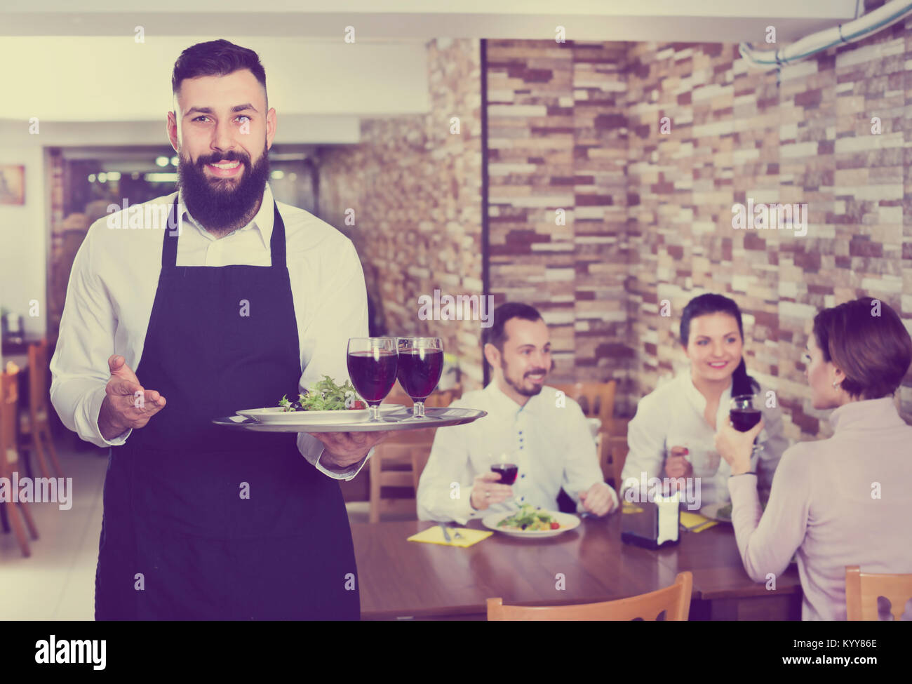 Cheerful waiter serving rural restaurant guests at the table Stock ...