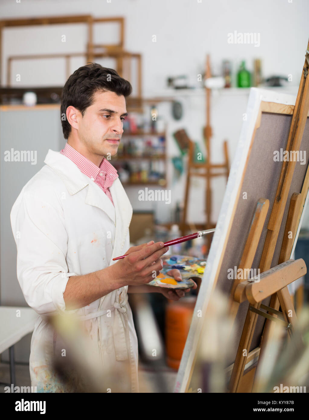 Happy art painter holding artist palette and painting on canvas Stock ...