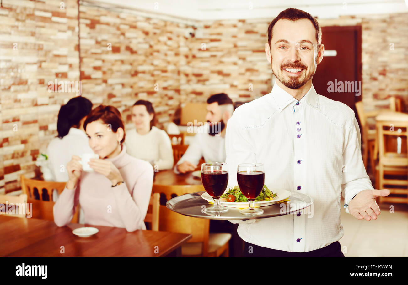 Cheerful happy waiter serving rural restaurant guests at table Stock ...